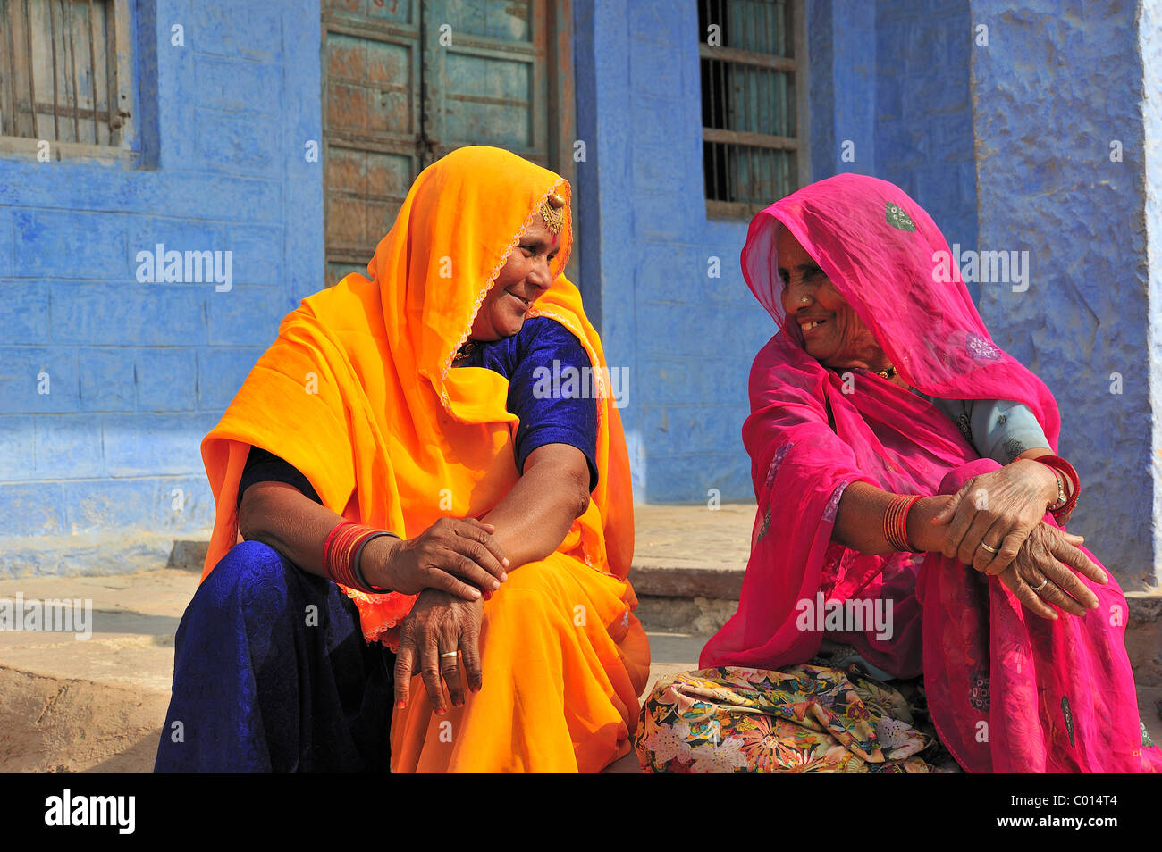 Two smiling Indian women wearing brightly coloured saris talking ...