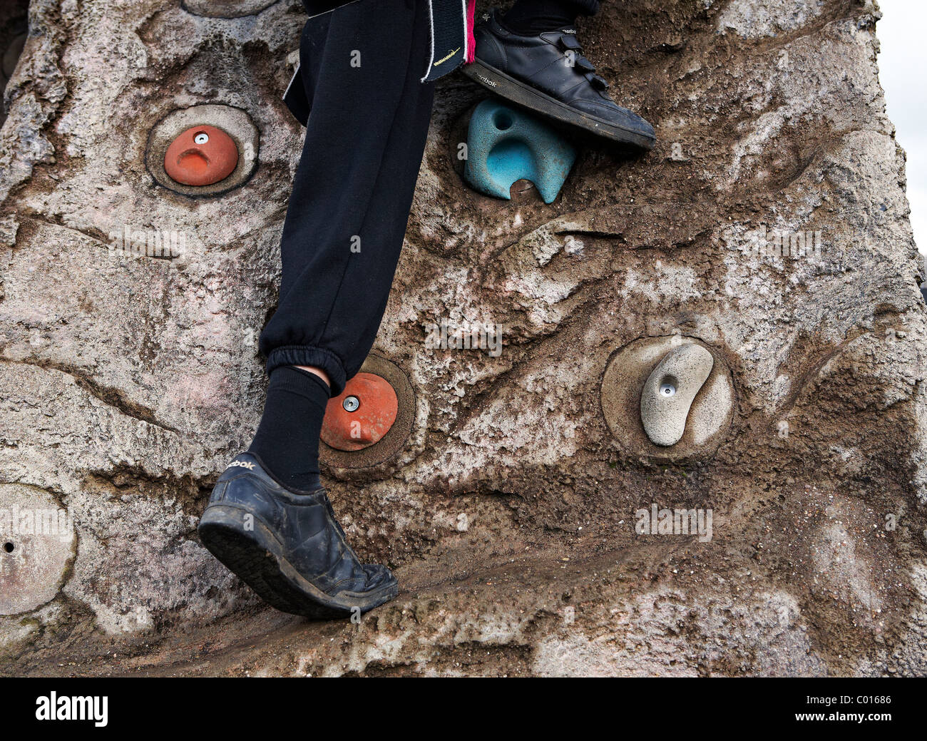 A young person makes their way up an out doors climbing wall Stock ...