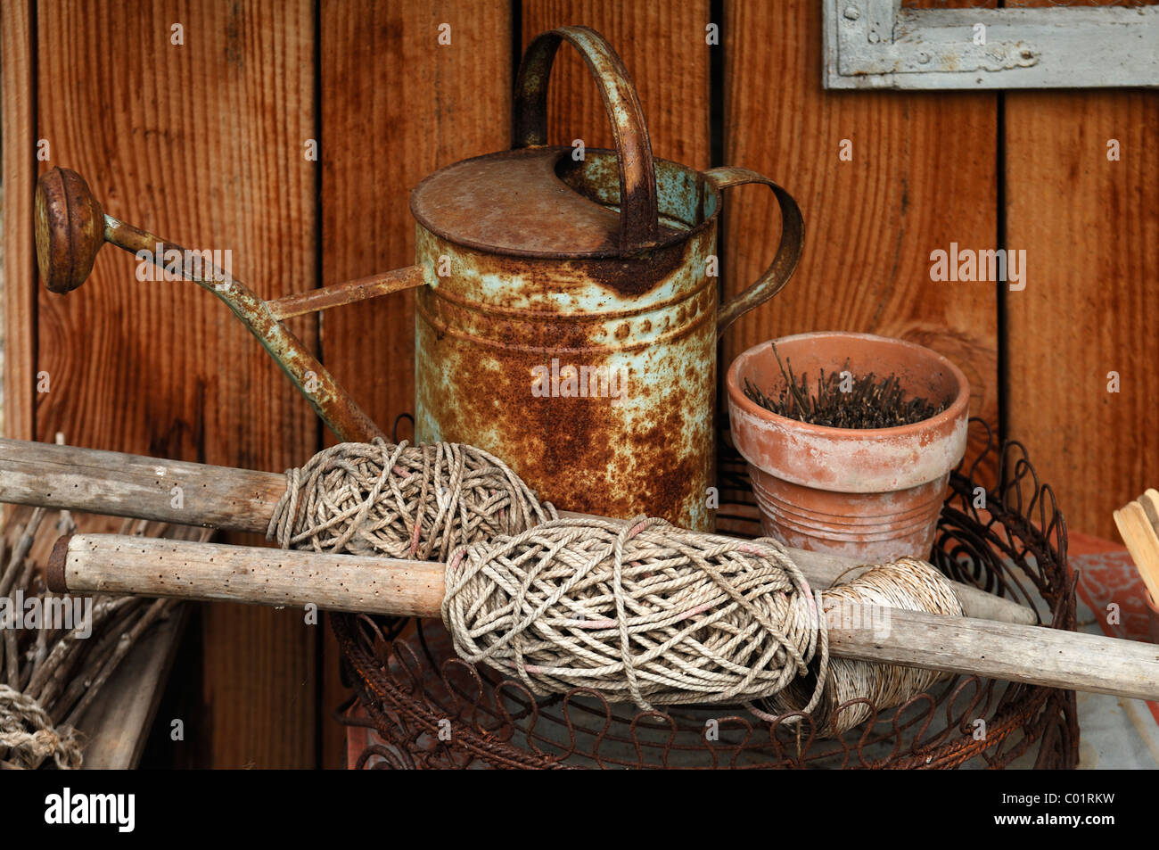 An old rusty watering can and rolled up plumb lines in front of a tool ...