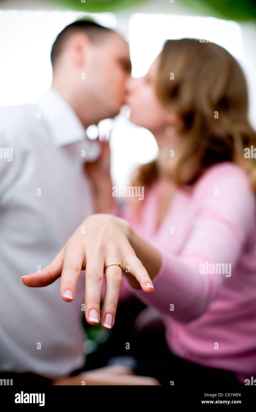Woman's hand with an engagement ring, kissing couple at the back Stock ...