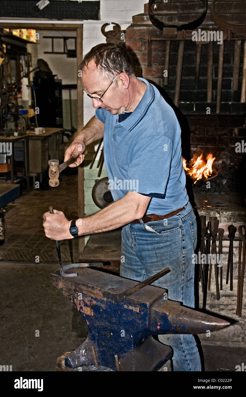 Using a pointed tool to make nail holes in a horseshoe Stock Photo - Alamy