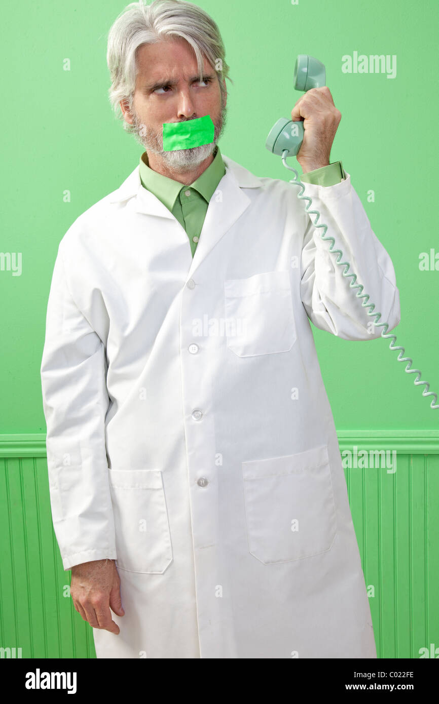 scientist with lab coat and green tape over mouth holding phone ...