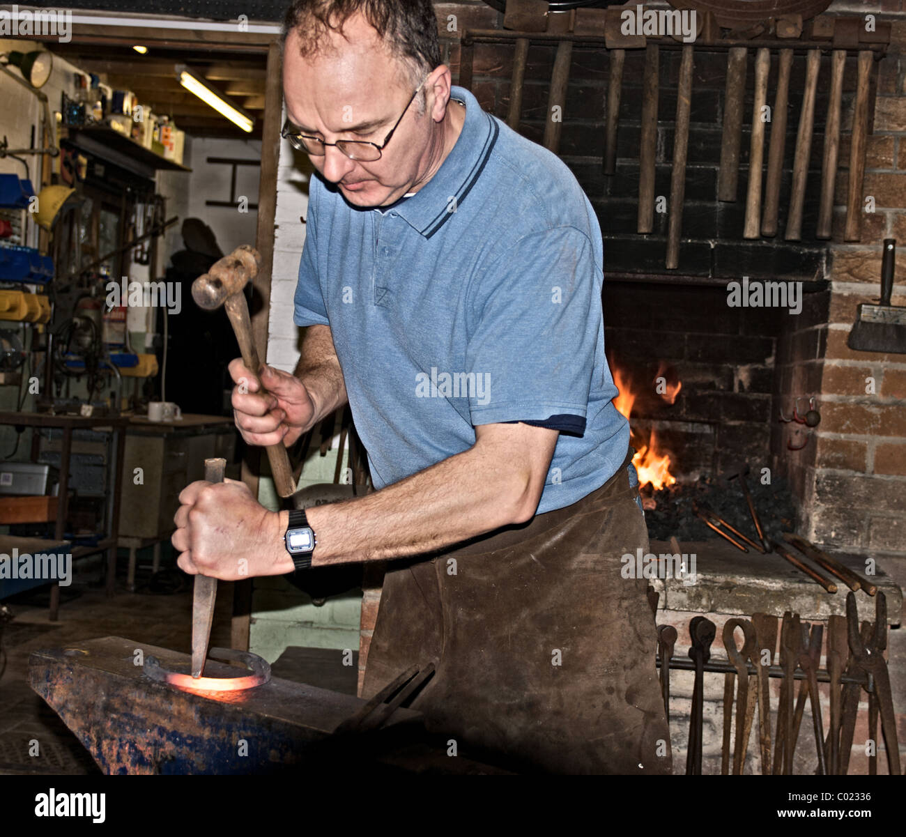 Blacksmith hammering a hole in the metal Stock Photo - Alamy