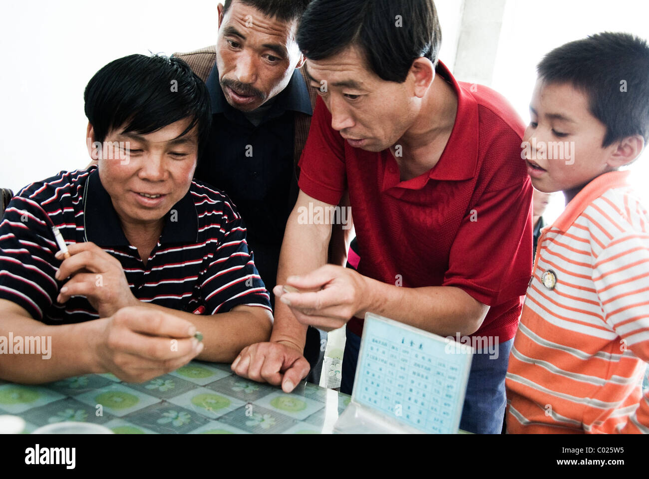 chinese men and boy looking at Euro coins in a restaurant in guyuan ...