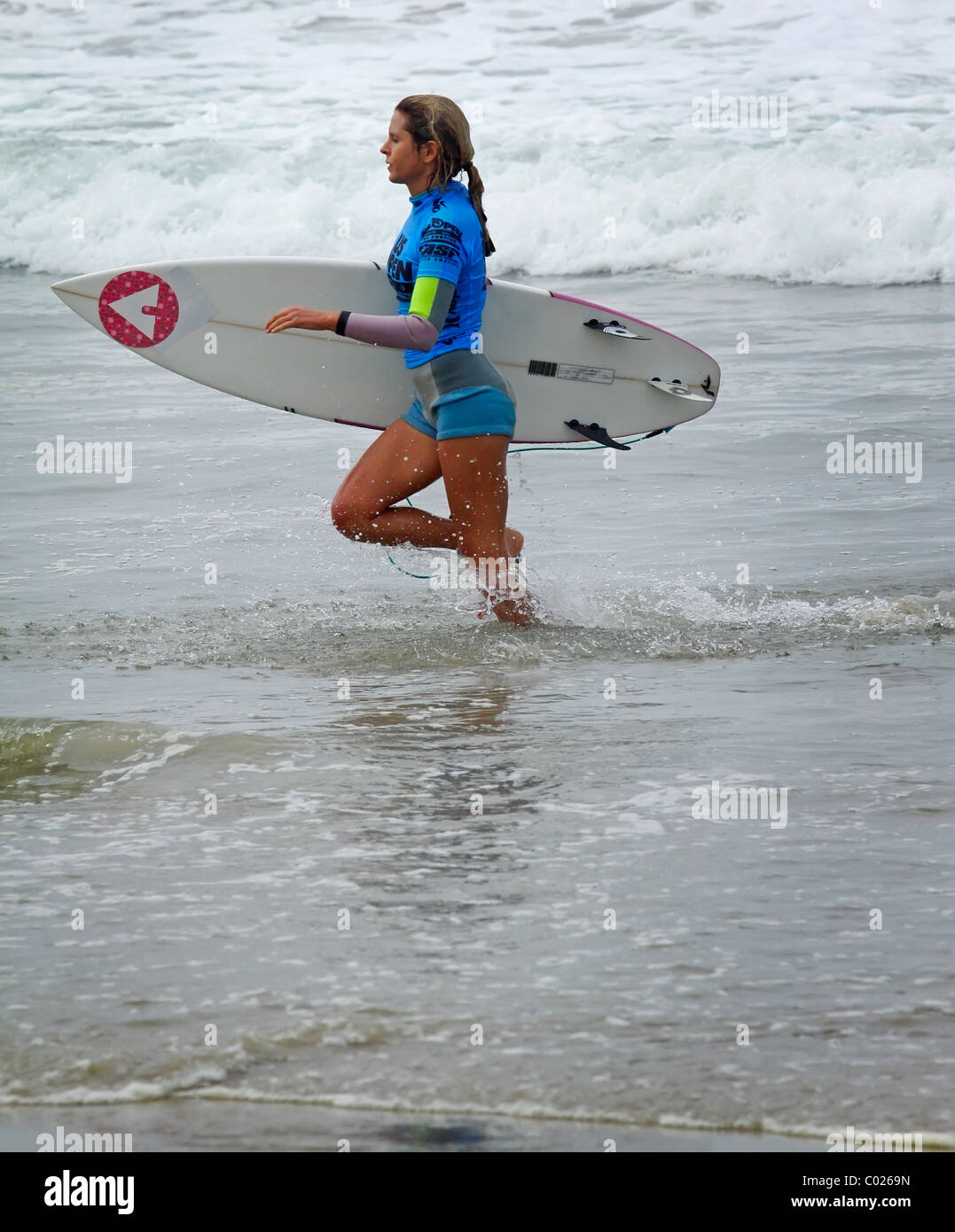 Female surfer running on the beach with surf board Stock Photo - Alamy
