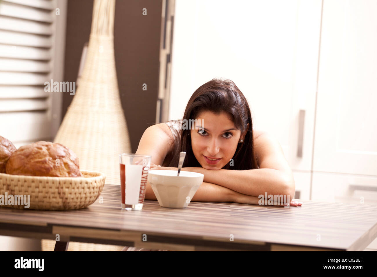 Young woman sitting comfortably at a dining table, having breakfast ...