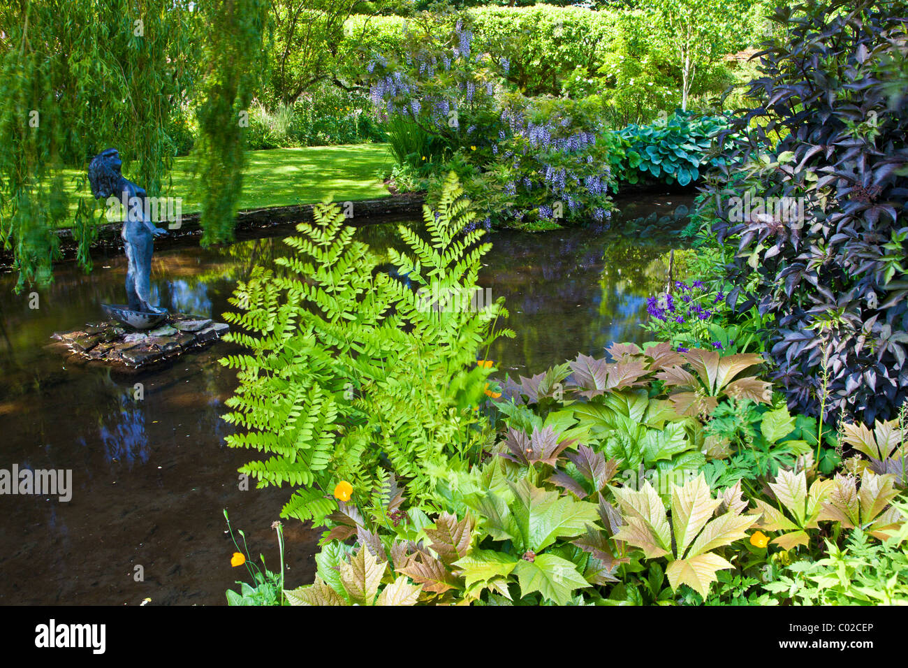 An ornamental garden pond in an English country garden with statue ...