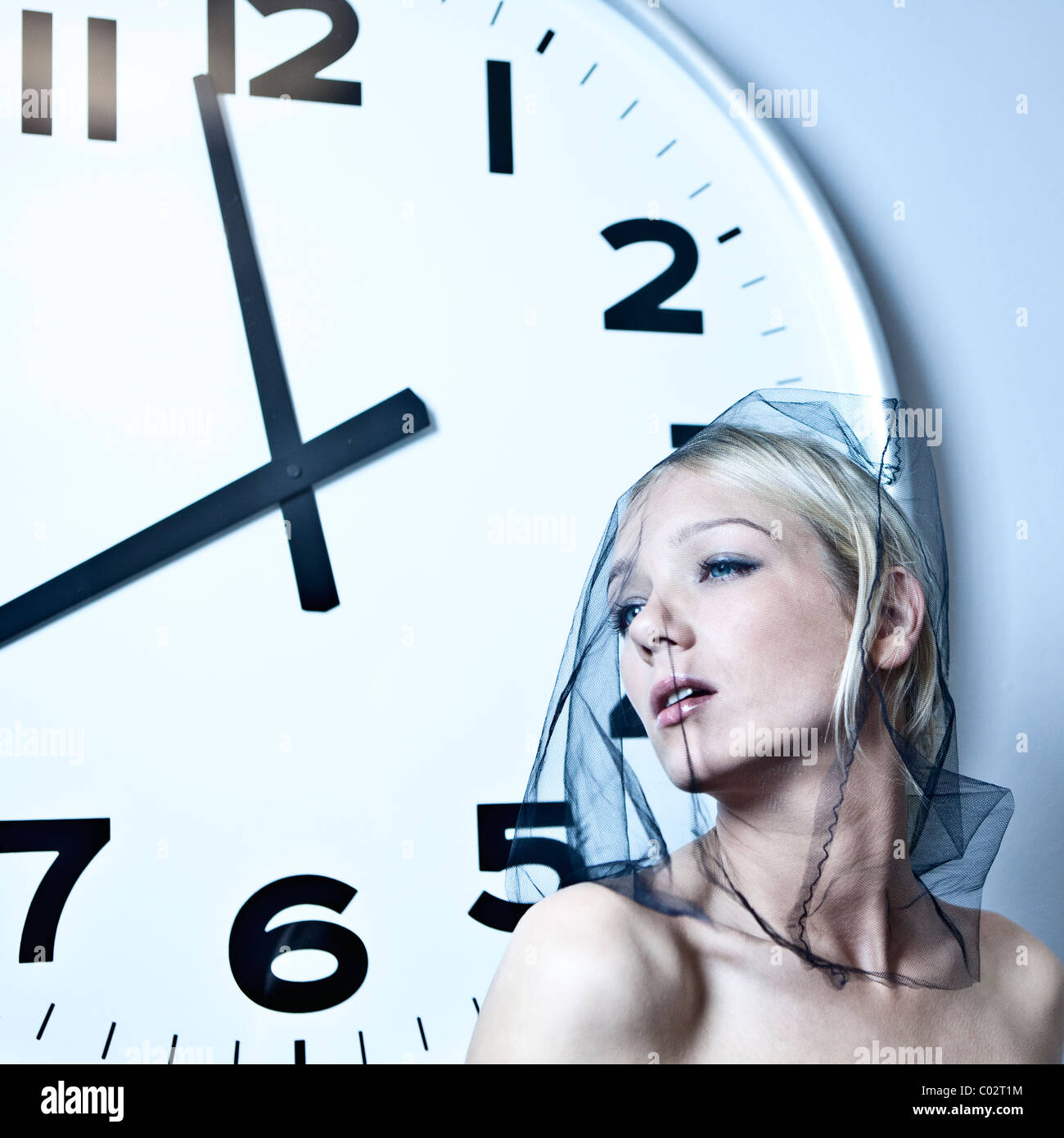 a woman with a veil over her face and a large clock behind Stock Photo ...