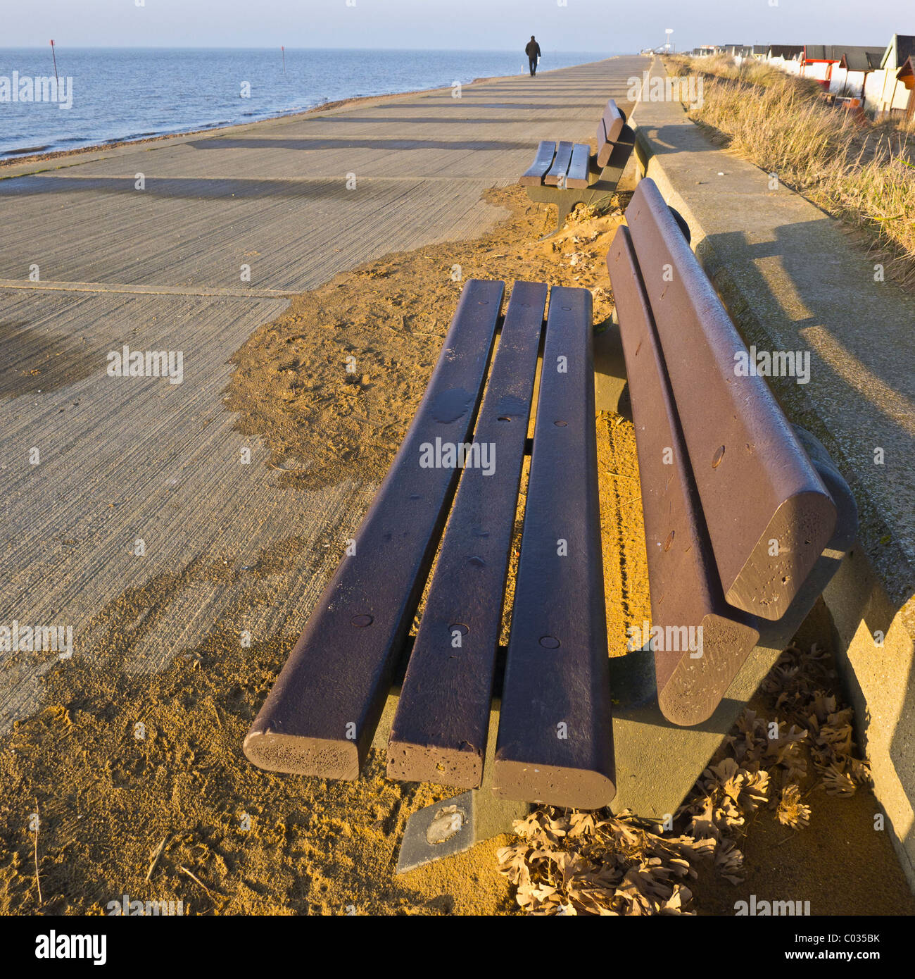 Man walking away from a bench along the promenade at Heacham on the ...