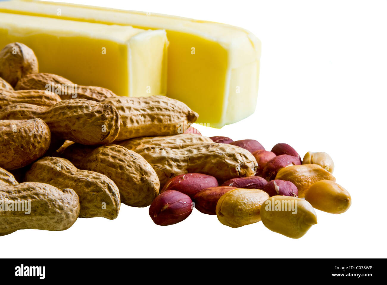 Closeup of peanuts in and out of shell with bars of butter on white ...