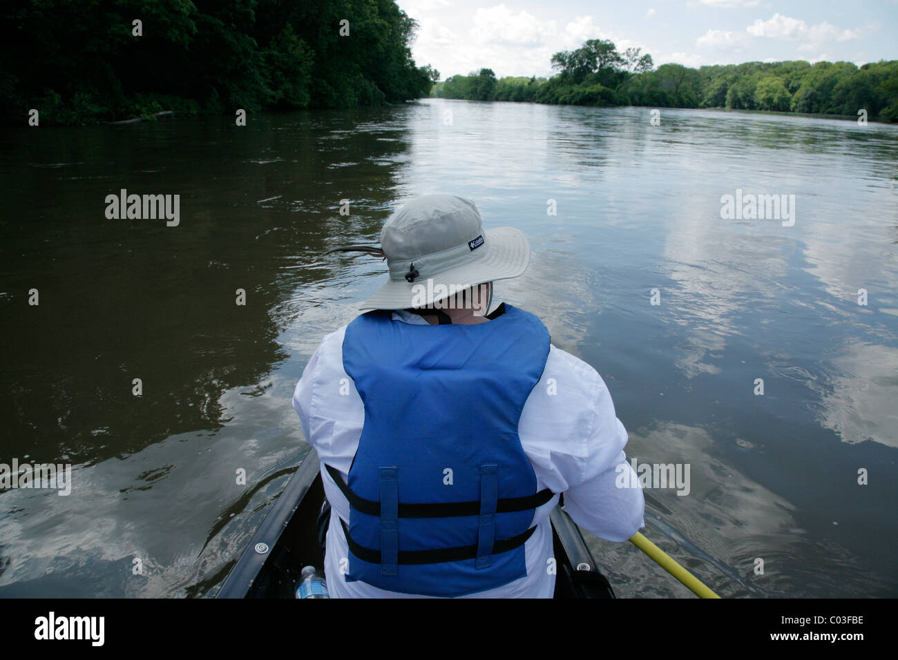 Back view of a man in the front of a canoe paddling on the Fox River ...