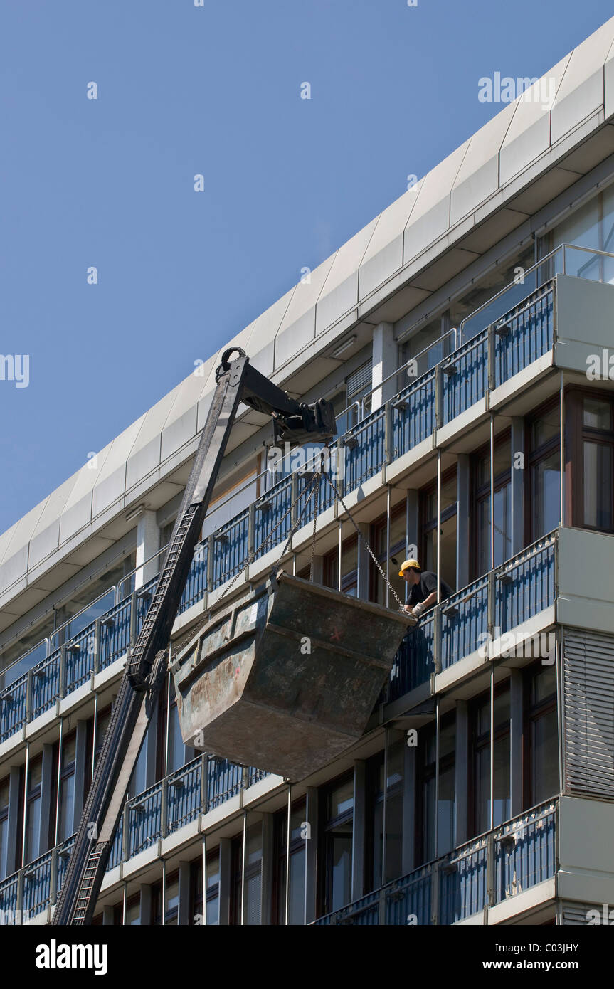 Construction waste container lifted by a crane to the top of a building ...