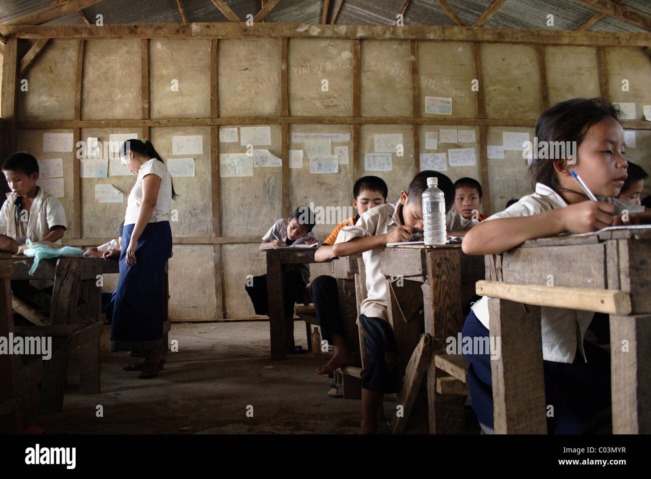 A low paid woman teacher is helping her students learn in a rundown ...