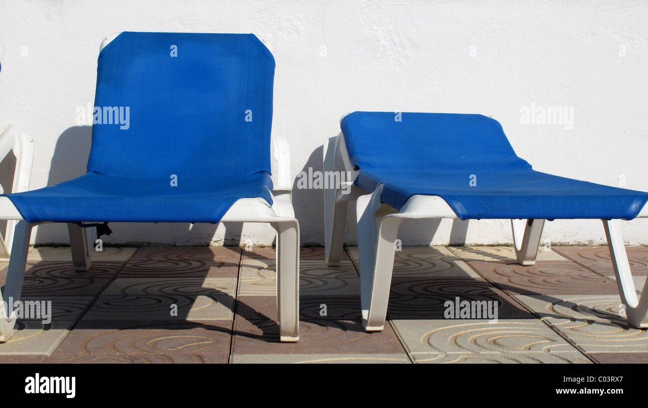 Two blue sun beds against a white wall Stock Photo - Alamy