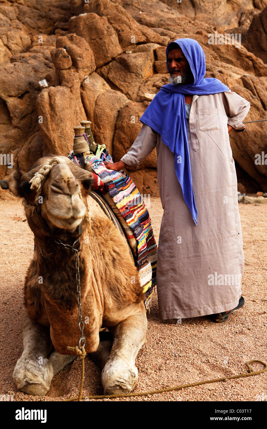 A Bedouin man wears a traditional dishdash and shimag. He stands by a ...