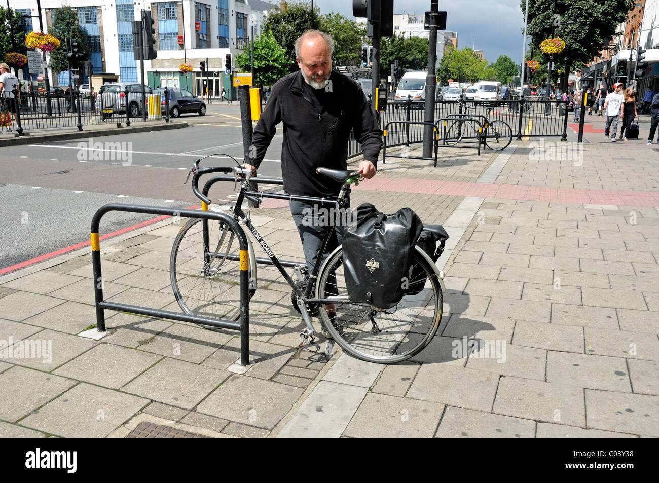 Man unlocking bike from cycle rack in Holloway Road Islington London ...
