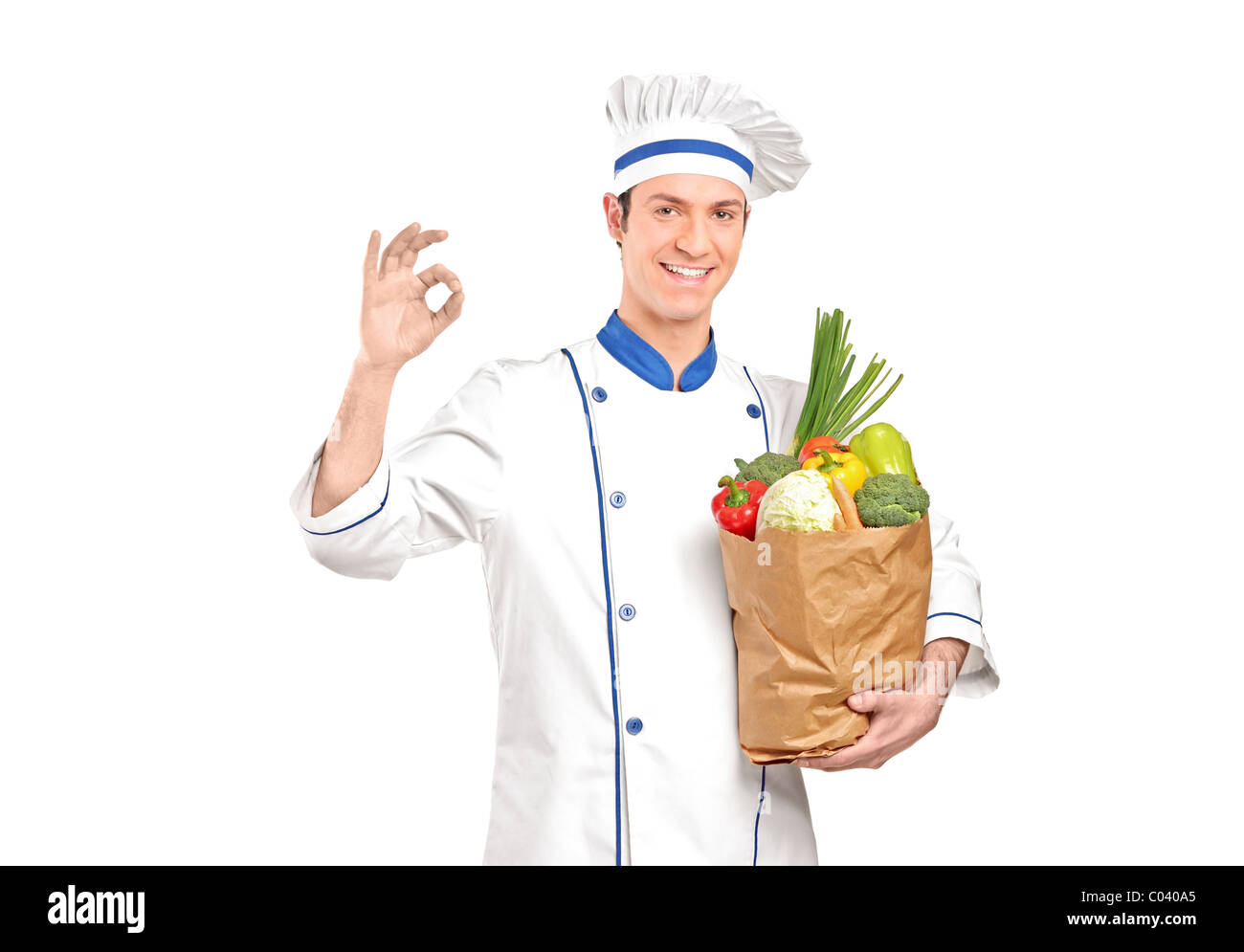 A smiling chef gesturing delicious hand sign and holding a grocery bag ...