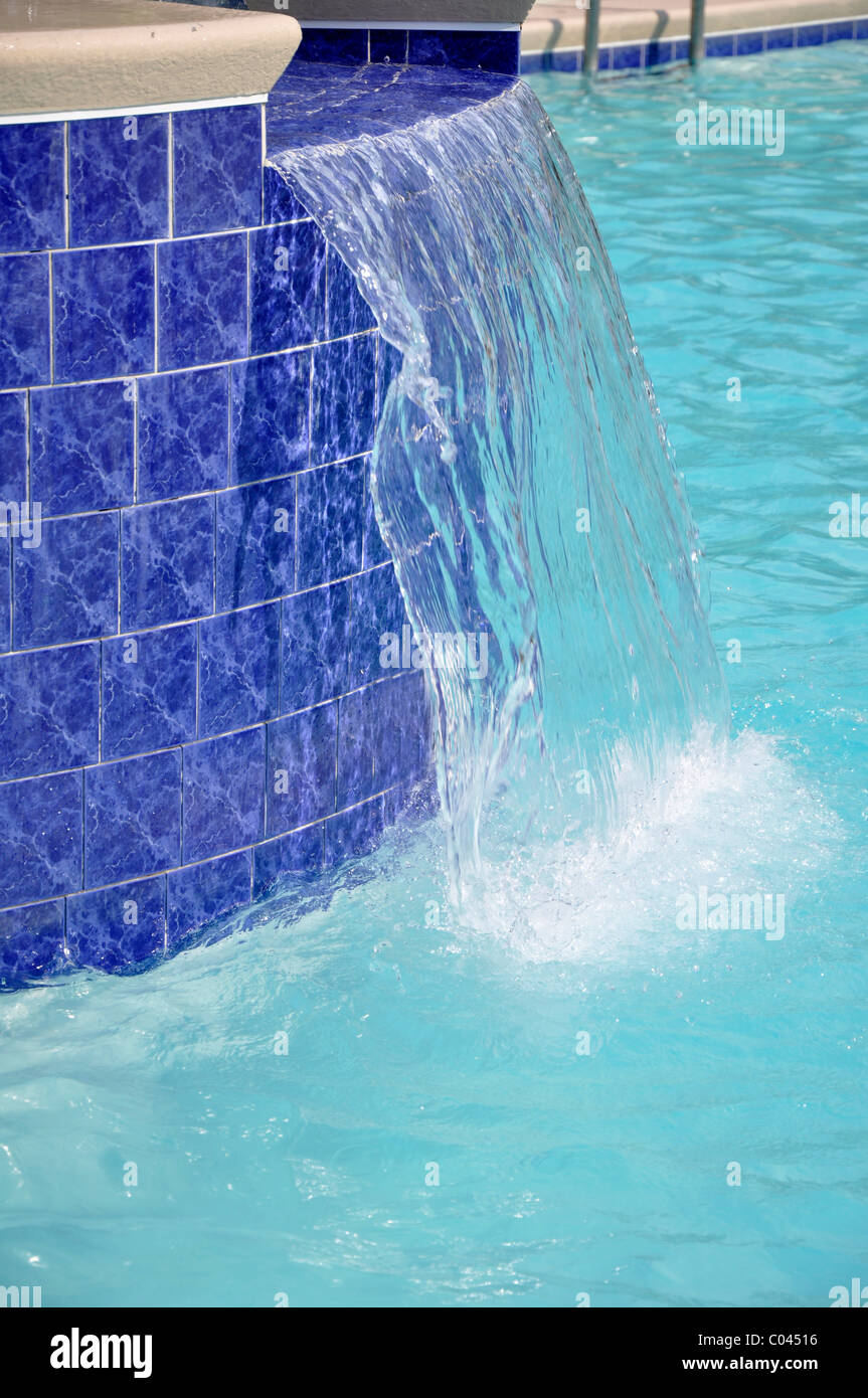 Water running off a tiled fountain in an inground pool.The tile is a ...