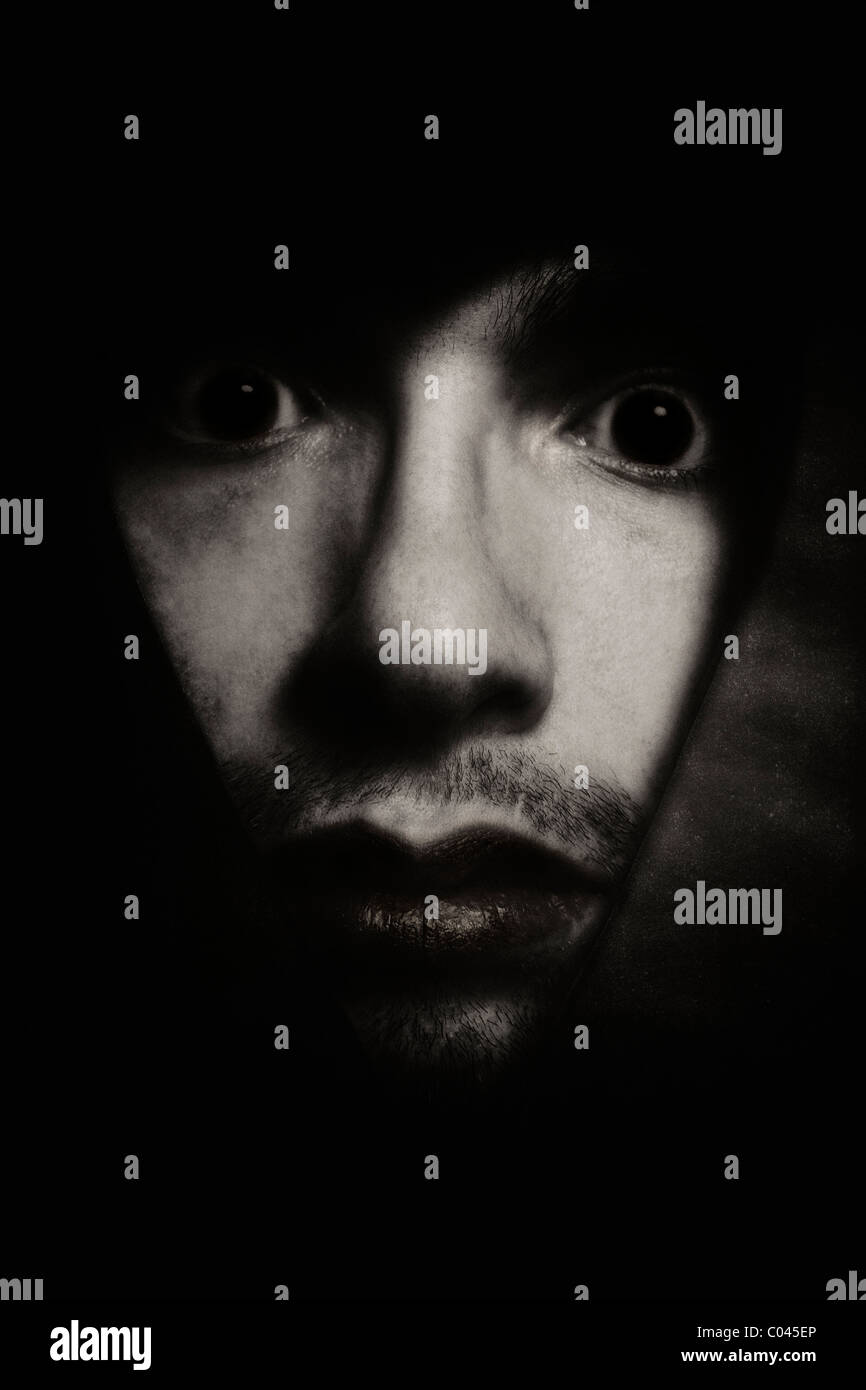 Face of young man peering from hole close up Stock Photo - Alamy