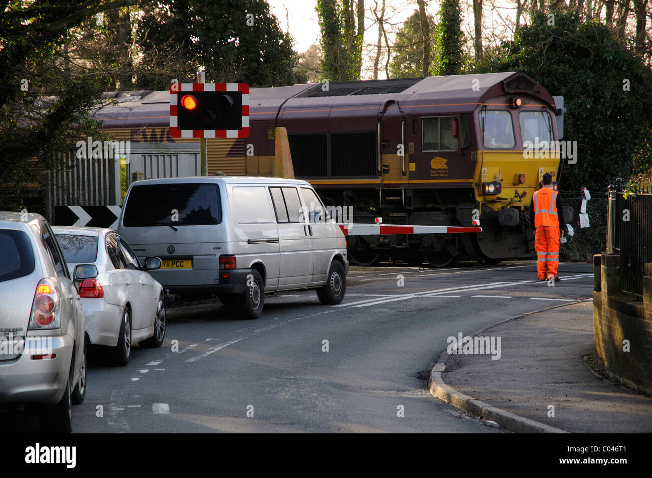 Railway employee in reflective safety clothing at a single barrier ...