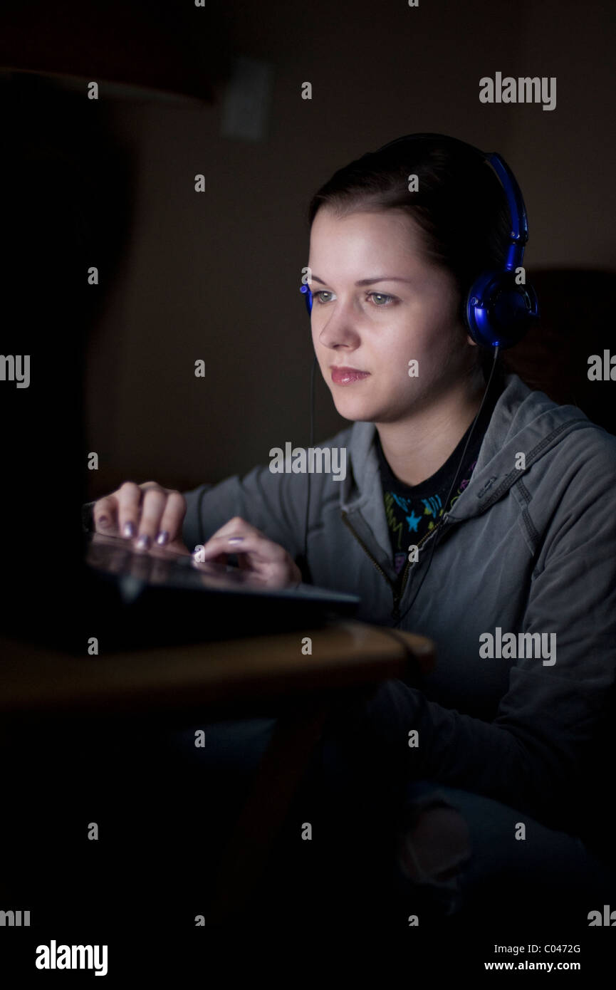 Teenager looking at computer screen in a darken living room Stock Photo ...