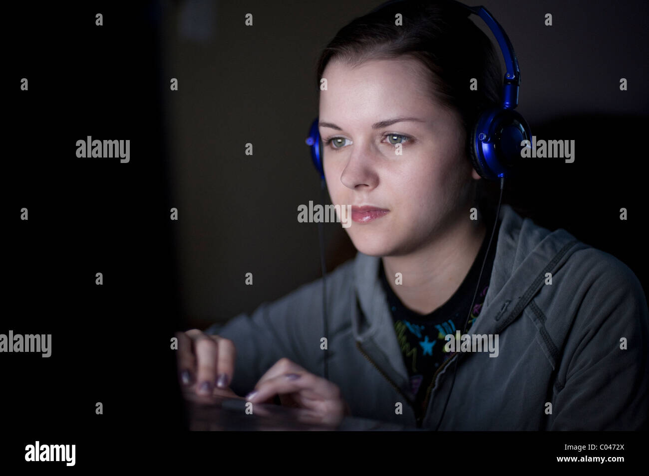 Teenager looking at computer screen in a darken living room Stock Photo ...