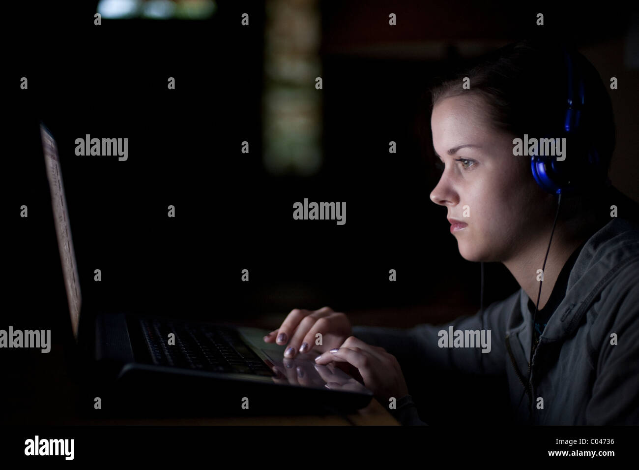 Teenager looking at computer screen in a darken living room Stock Photo ...