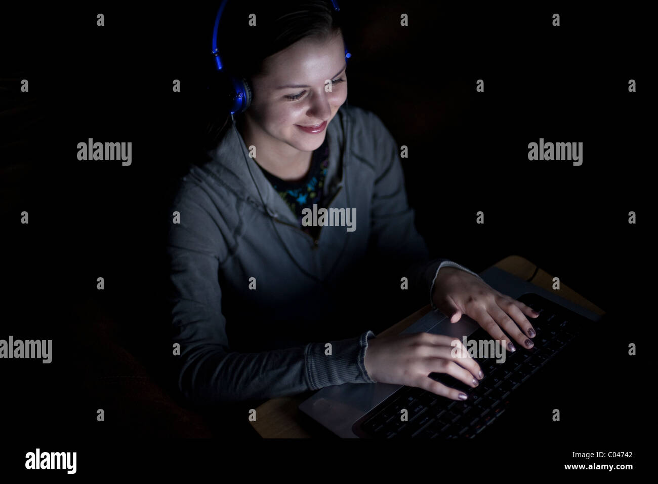 Teenager looking at computer screen in a darken living room Stock Photo ...