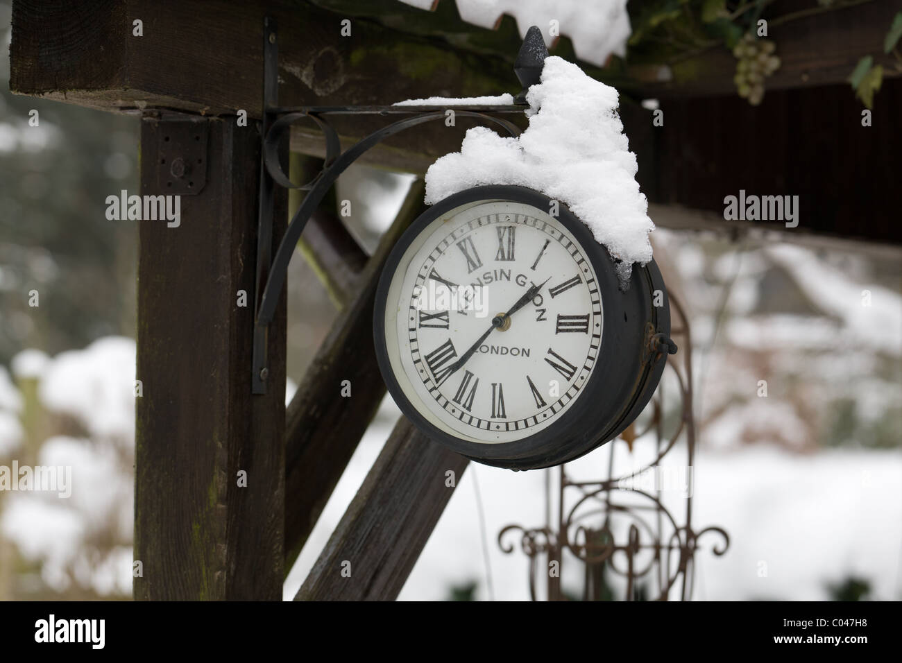 antique clock covered with snow in a garden Stock Photo - Alamy
