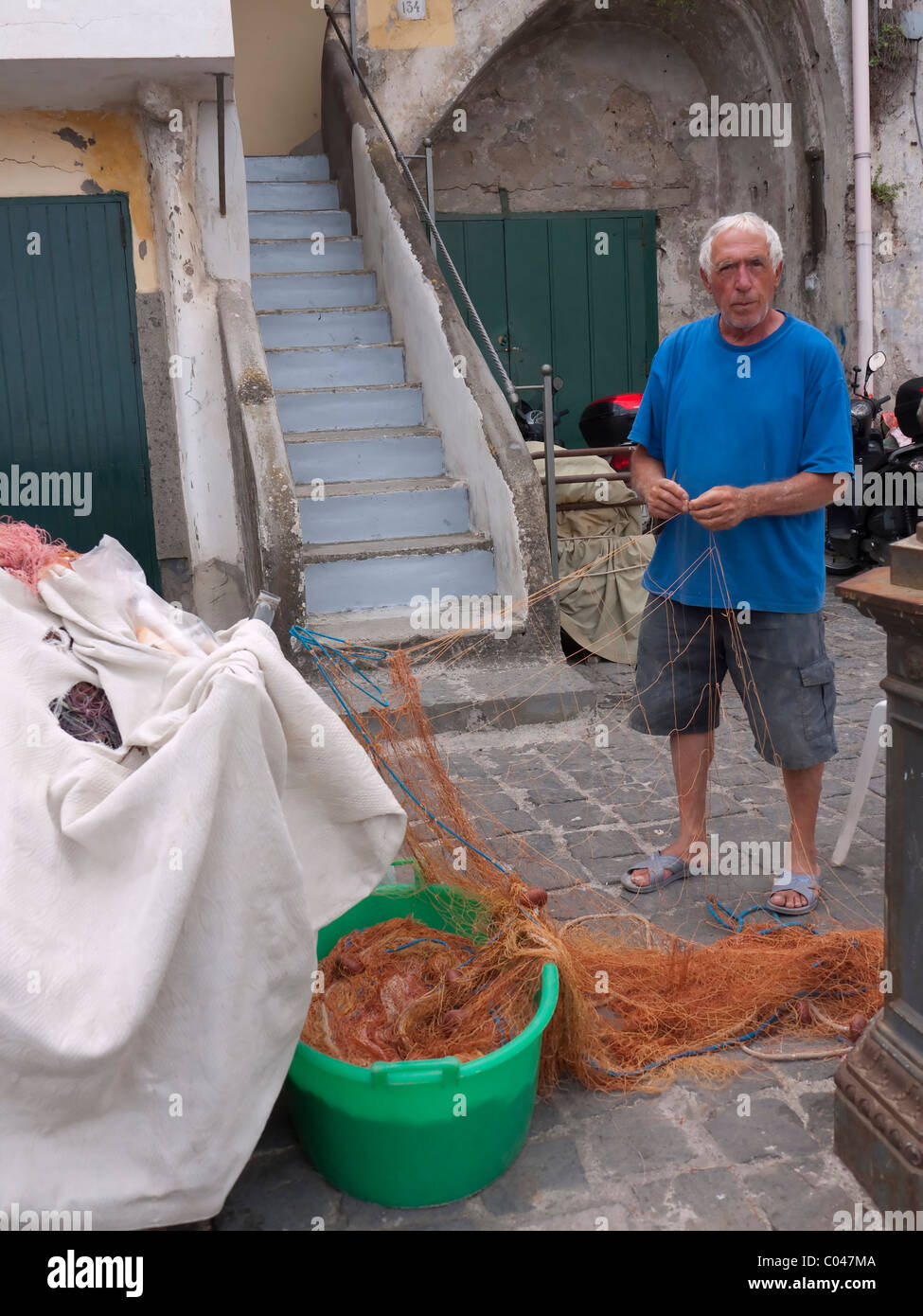 Fisherman mending nets in the original fishing harbour of Marina Grande ...