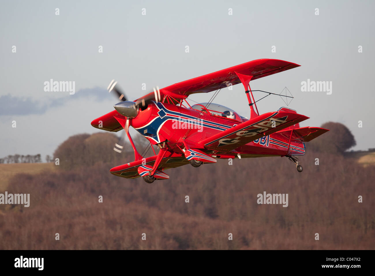 An aerobatic red Pitts S2-C biplane flying at Compton Abbas airfield in ...
