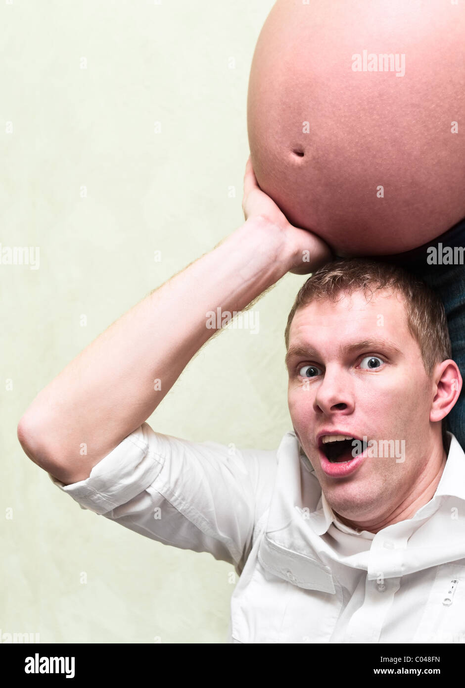 Pregnant woman with her amazed husband holding belly his hands ...