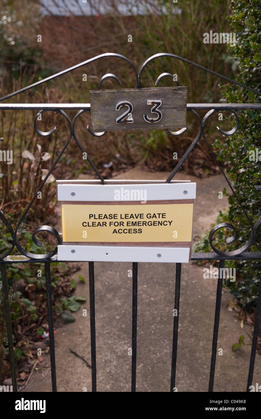 A sign on a Uk gate reading please leave gate clear for emergency ...