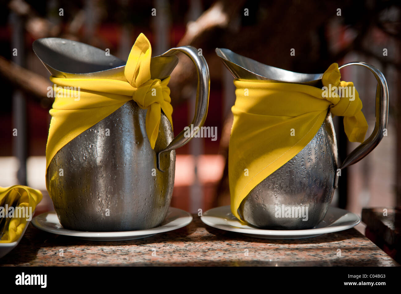 Two silver cool water pitchers wrapped with yellow napkins Stock Photo ...