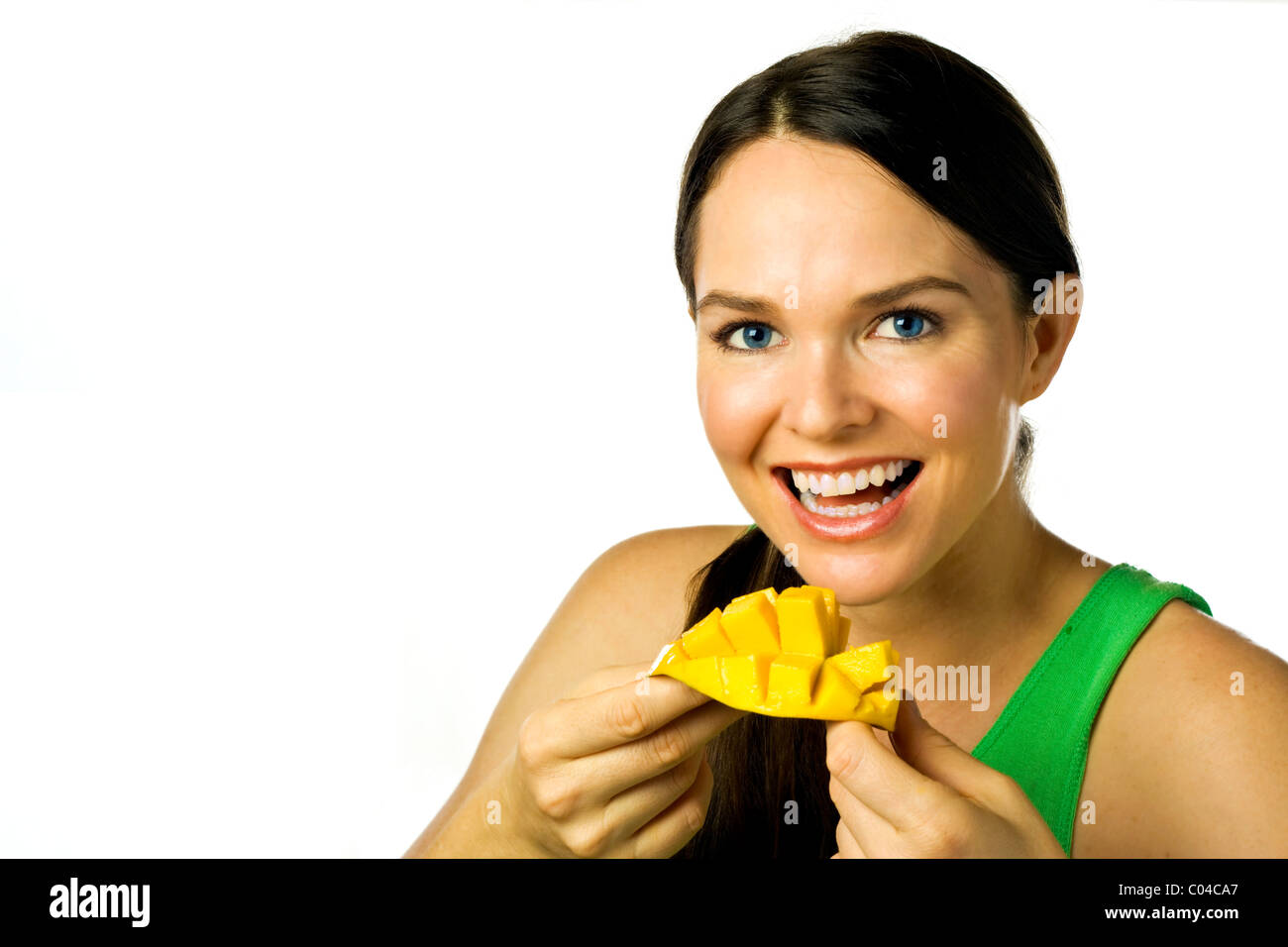 Young beautiful and happy woman eating a mango isolated over white ...