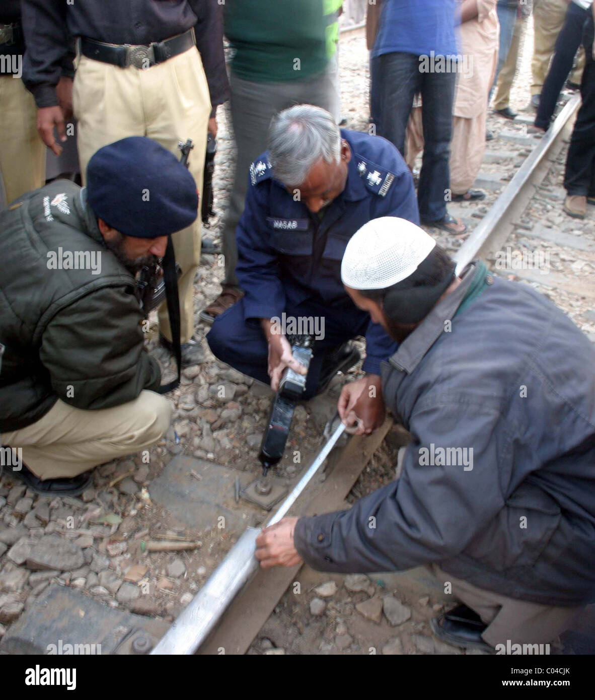 Police officials inspect a damaged railway track which was destroyed in ...
