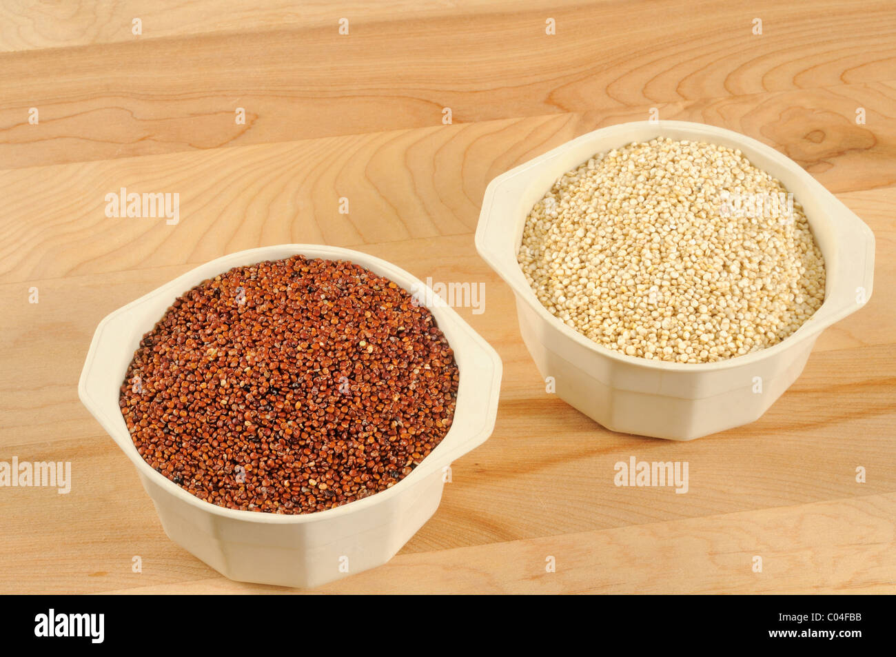 Small containers filled with uncooked red and white quinoa on a cutting ...