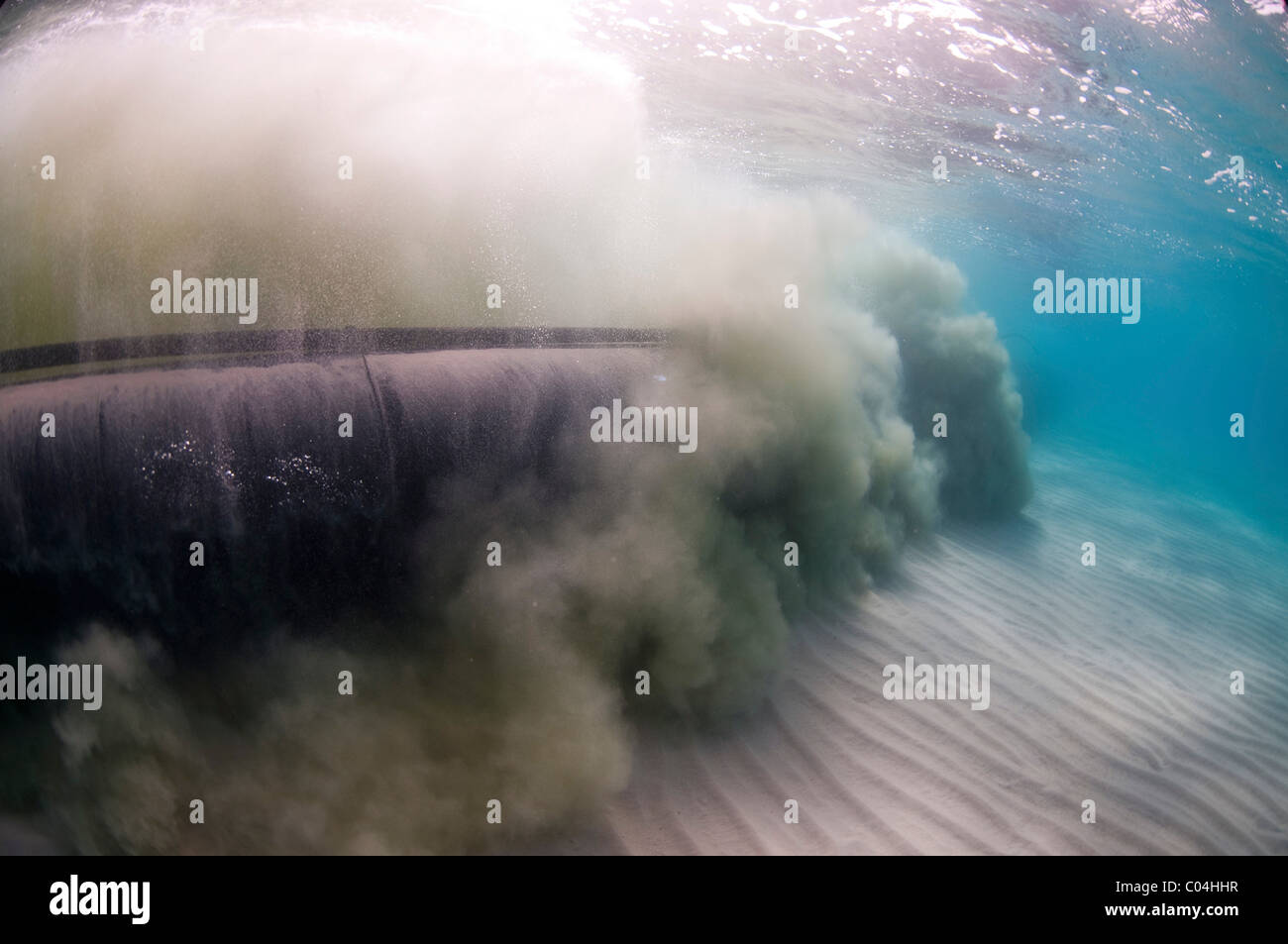 Workers laying a brine discharge pipe from a desalination plant on the ...