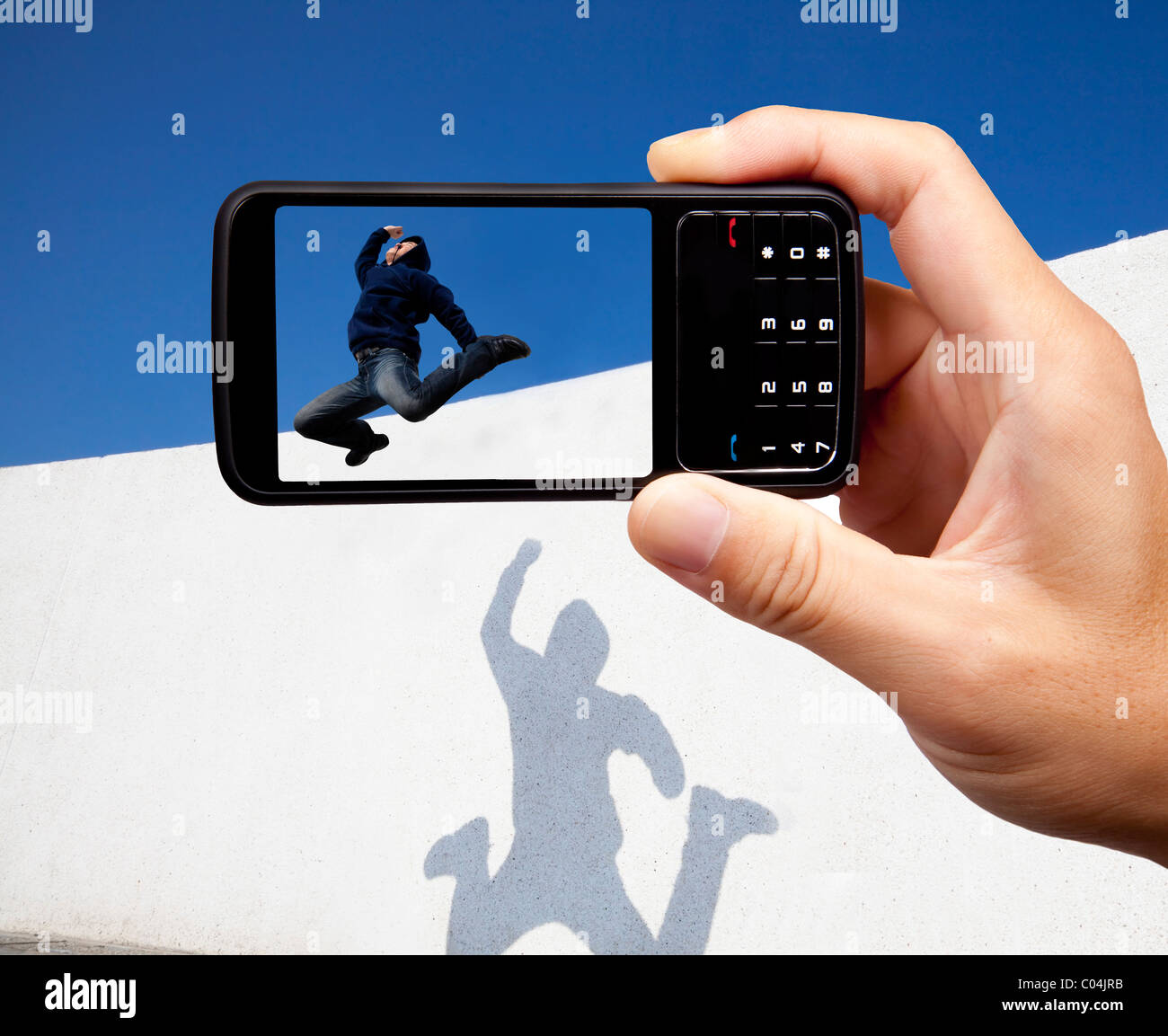 Taking picture by mobile phone and young jumper Stock Photo - Alamy