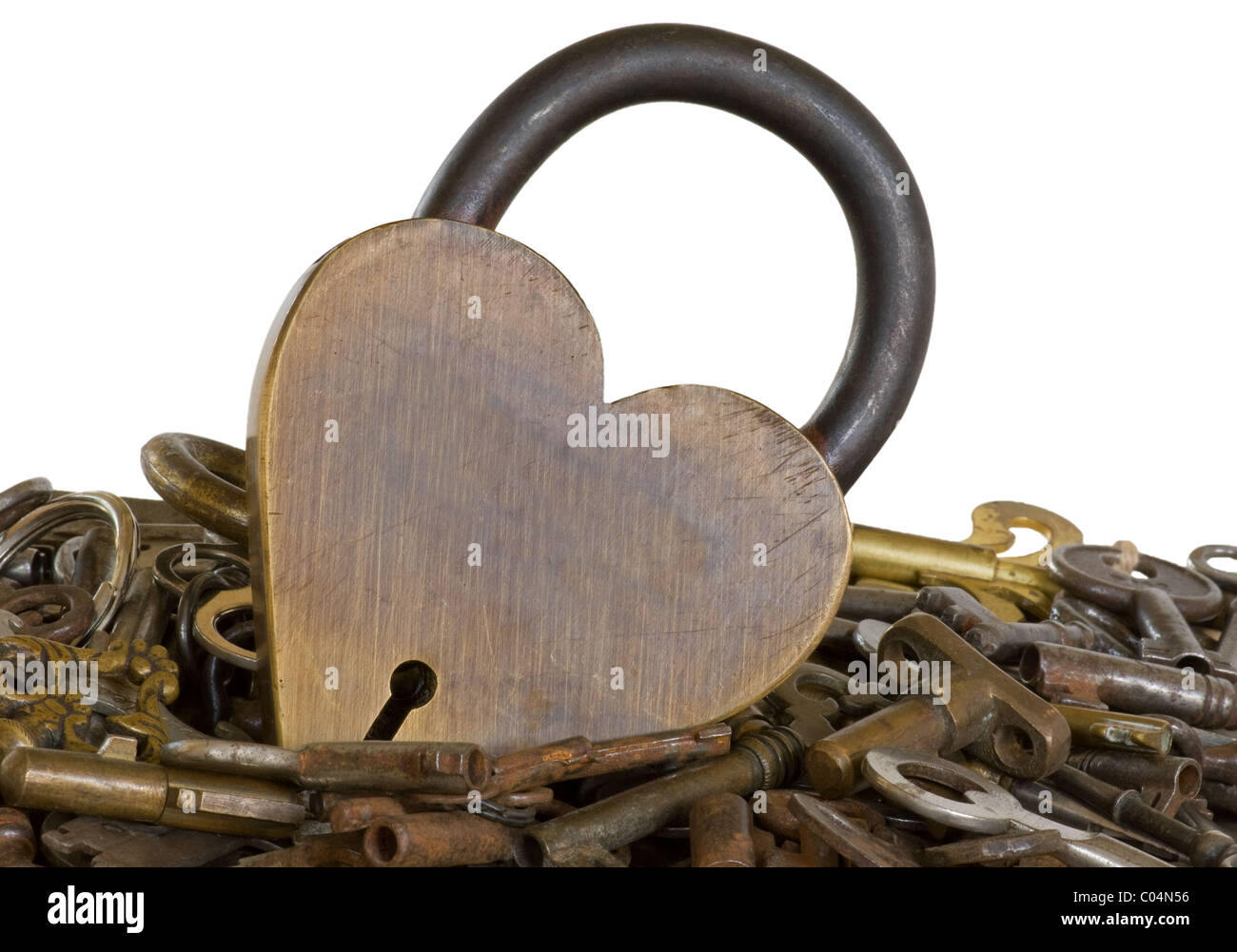 A brass tinted heart lock rests on a pile of old keys. Finding the ...