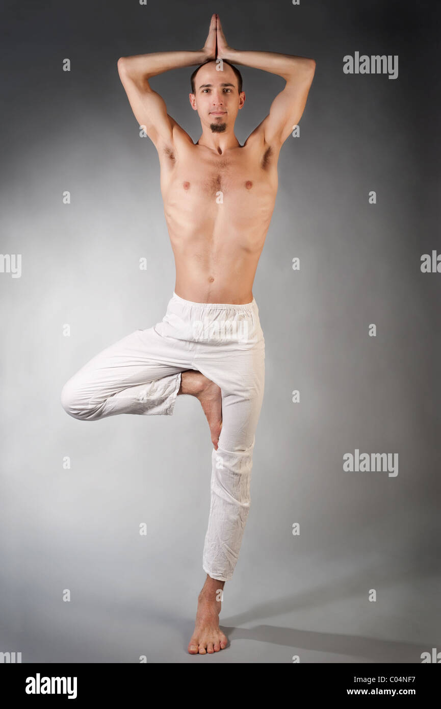 Handsome young man in yoga position. Studio portrait over gray ...