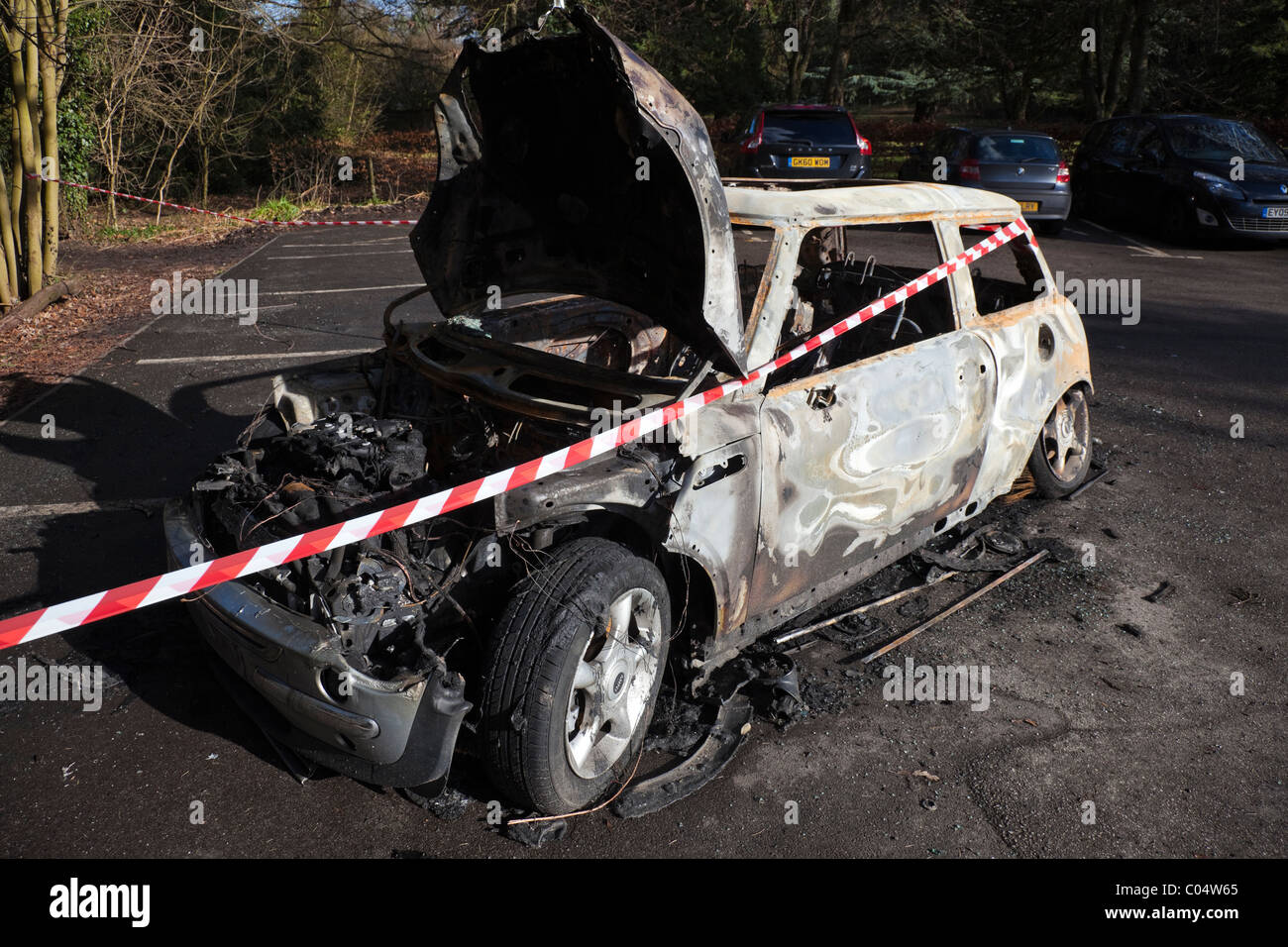 Burnt-out Mini car in a car park, probably abandoned and vandalised by ...