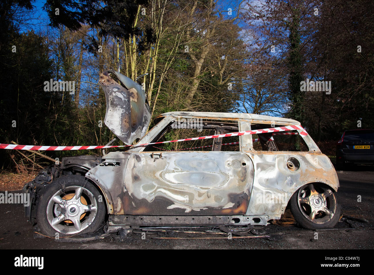 Burnt-out Mini car in a car park, probably abandoned and vandalised by ...