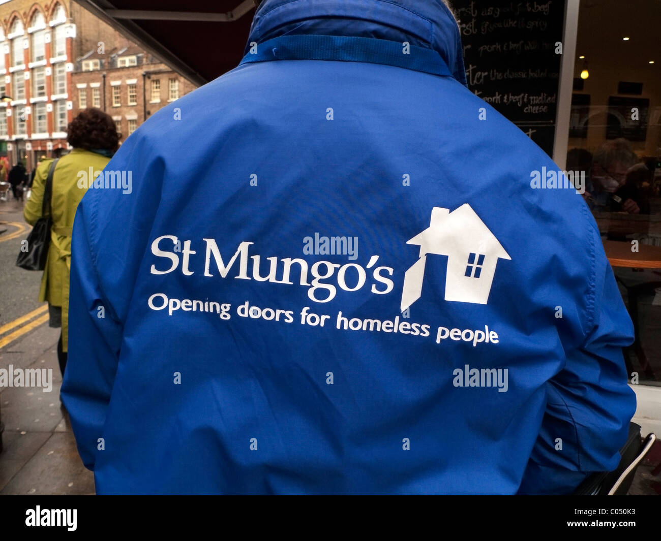 Rear view of a St Mungo's logo on the blue jacket of a chugger working ...