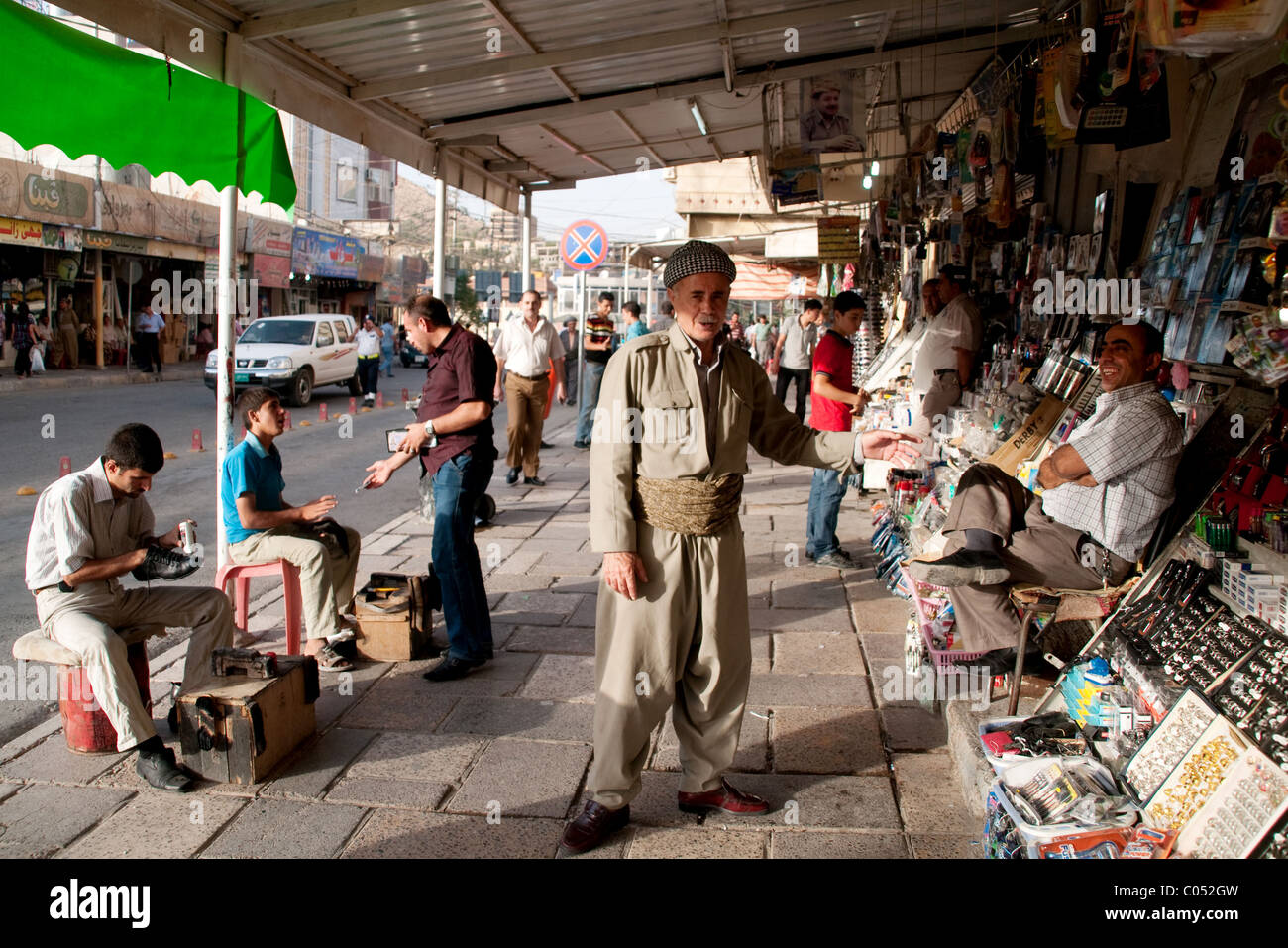 Street merchants and store owners on a sidewalk in the Kurdish city of ...