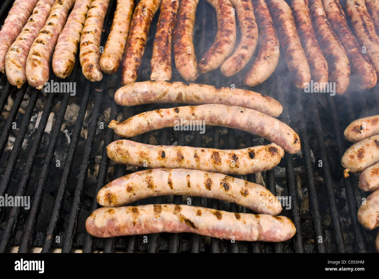 Barbecued sausages saucissons being cooked on griddle for sale as snack ...
