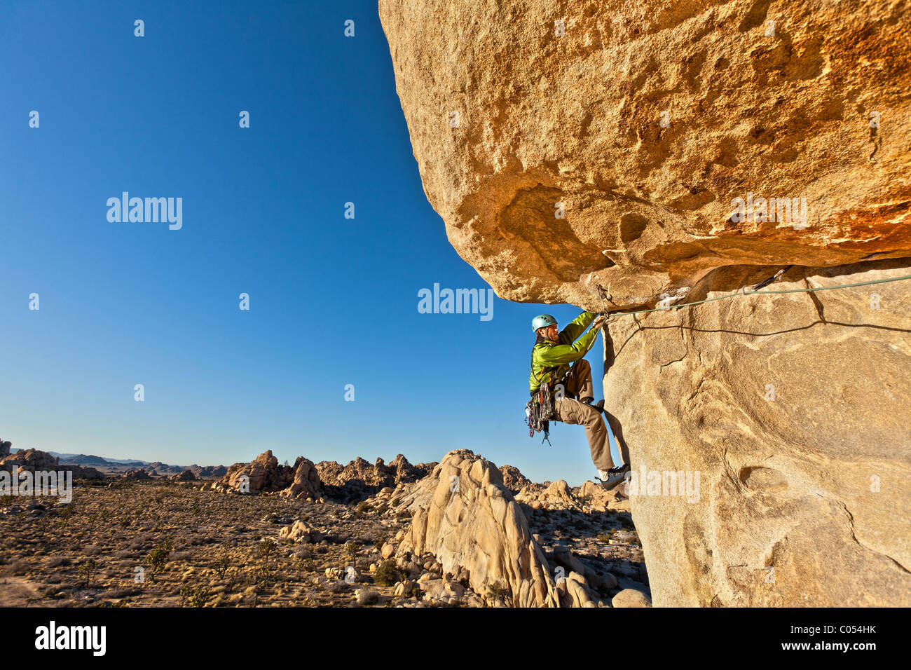 Male rock climber struggles for his next grip as he clings to a sheer ...