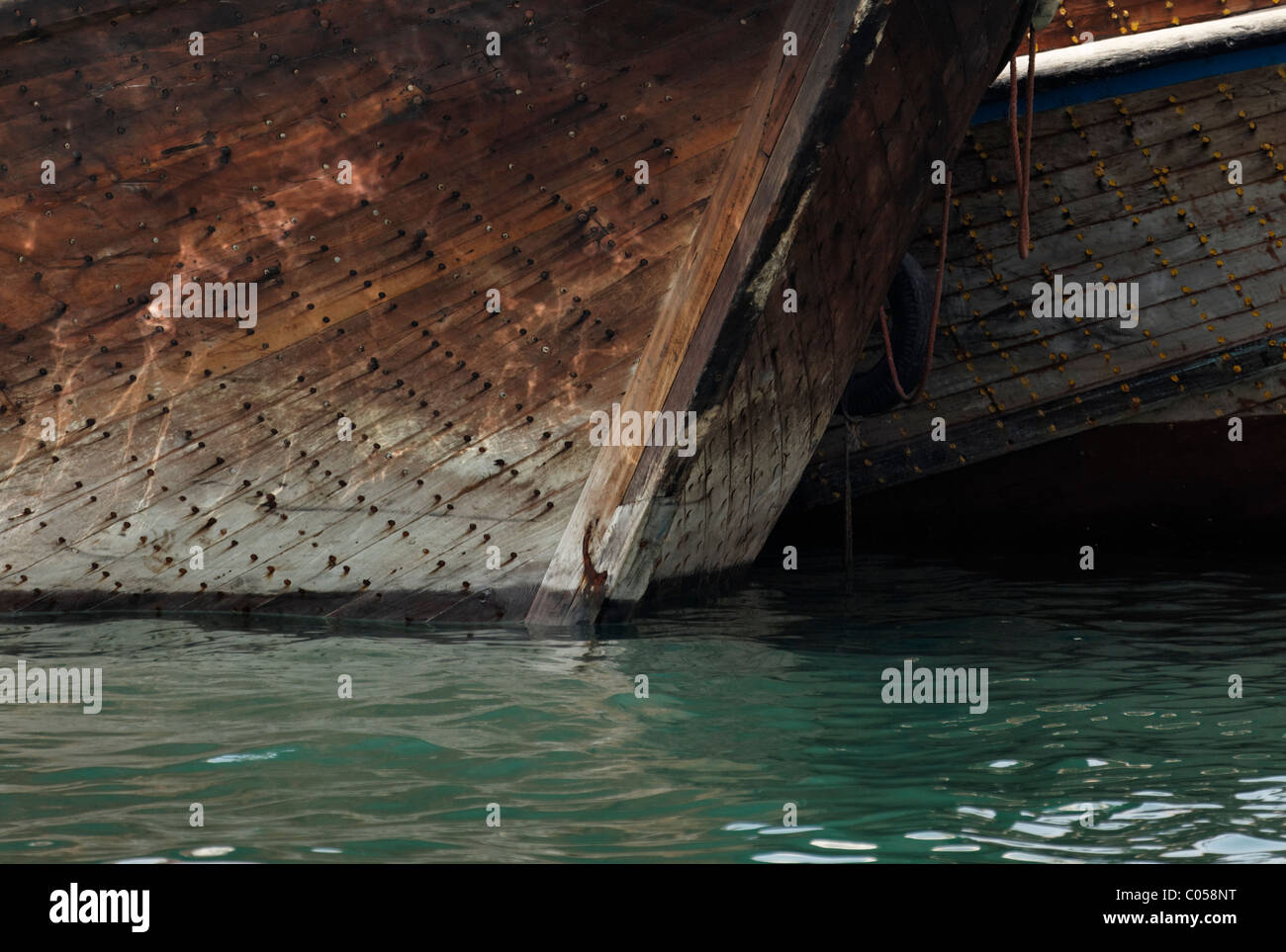 Sunlight reflected onto the wooden hull of a traditional dhow moored on ...