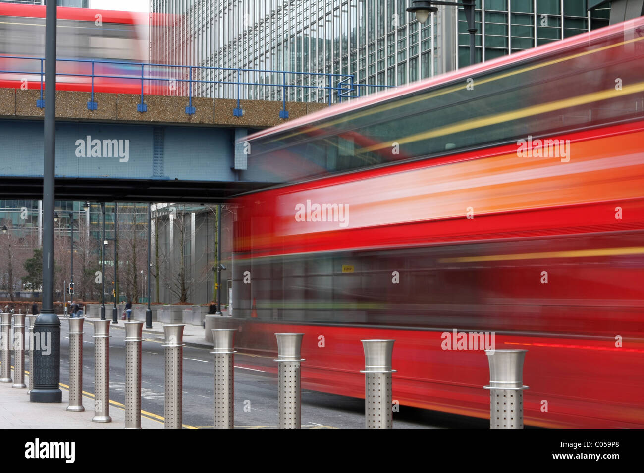 A blurred bus going under a bridge and a blurred DLR train going over ...