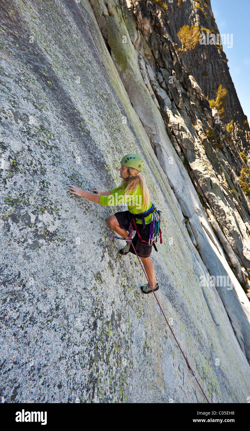 Female rock climber struggles for her next grip on the edge of a steep ...